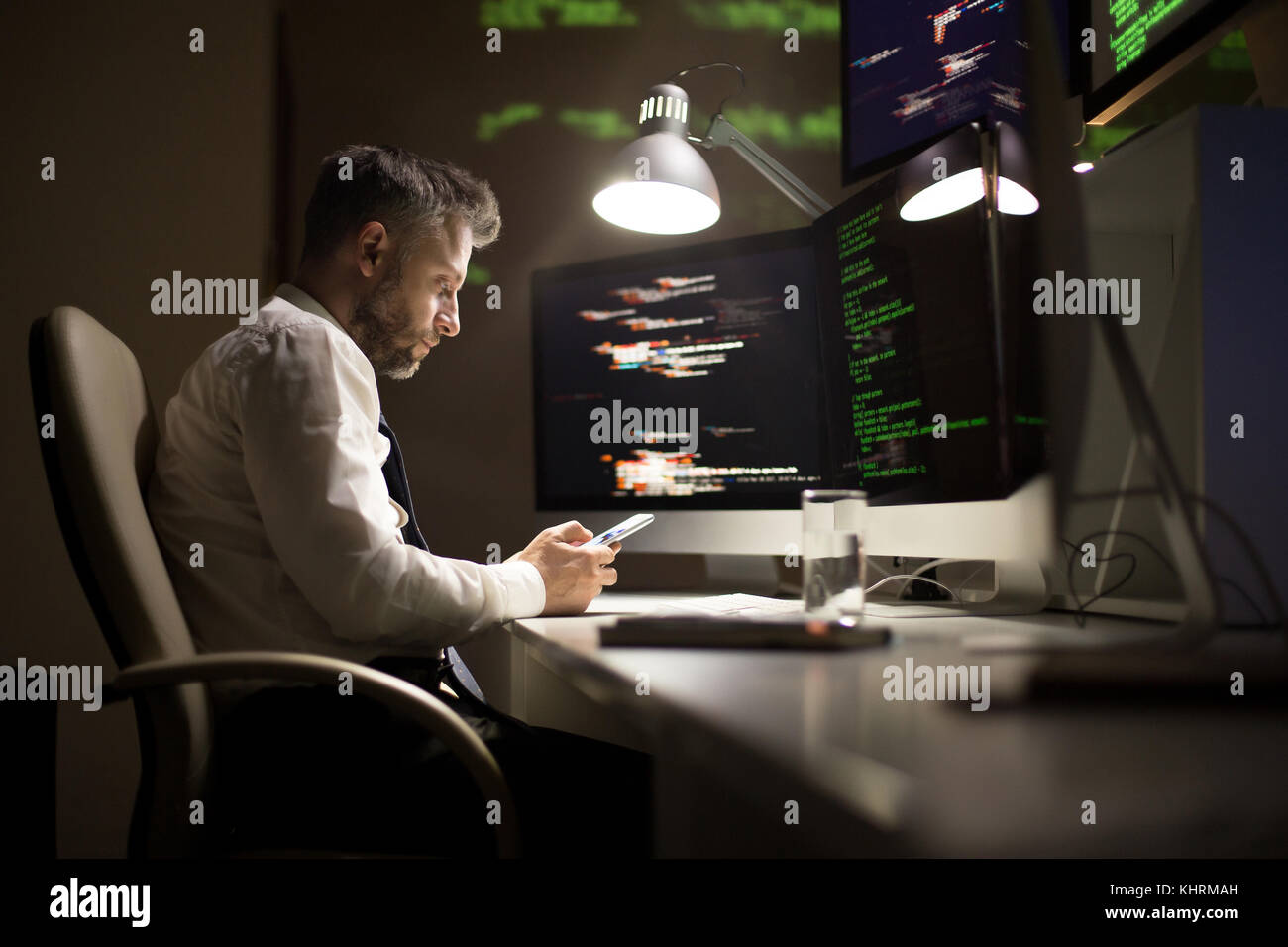 Profile view of talented middle-aged programmer using smartphone while ...
