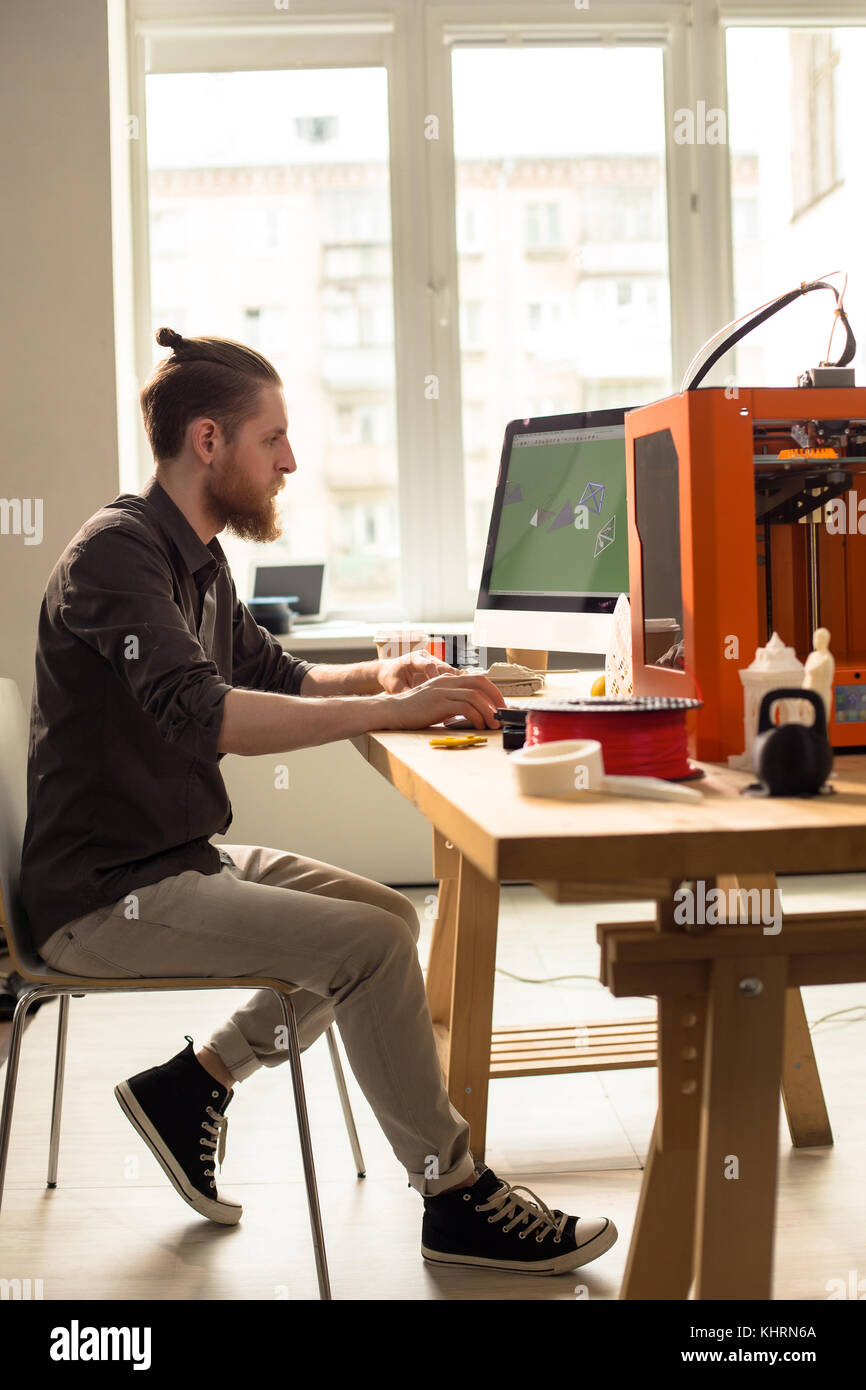 Full length portrait of concentrated young designer sitting in front of ...