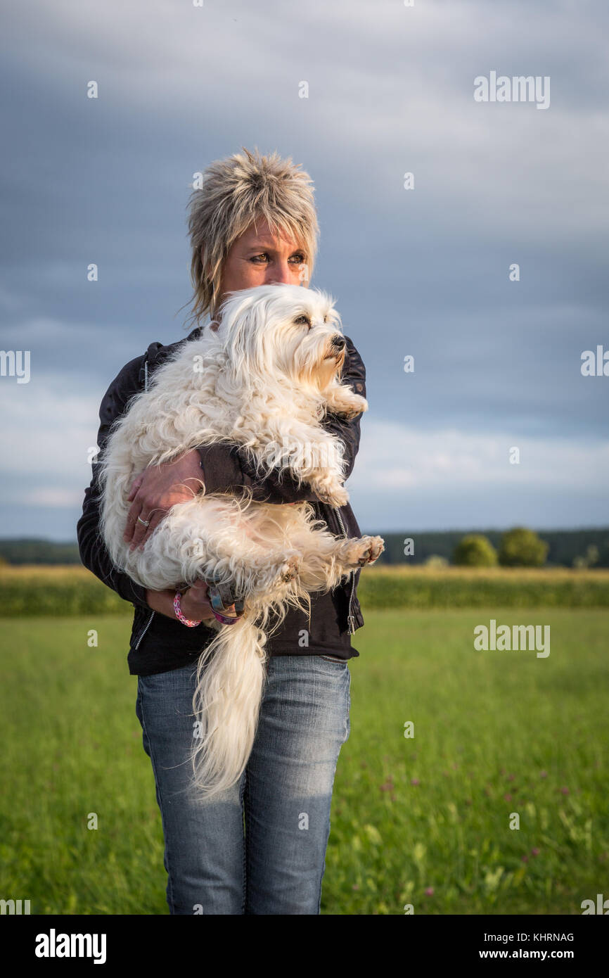 A woman holds her little weißn dog in her arms Stock Photo - Alamy