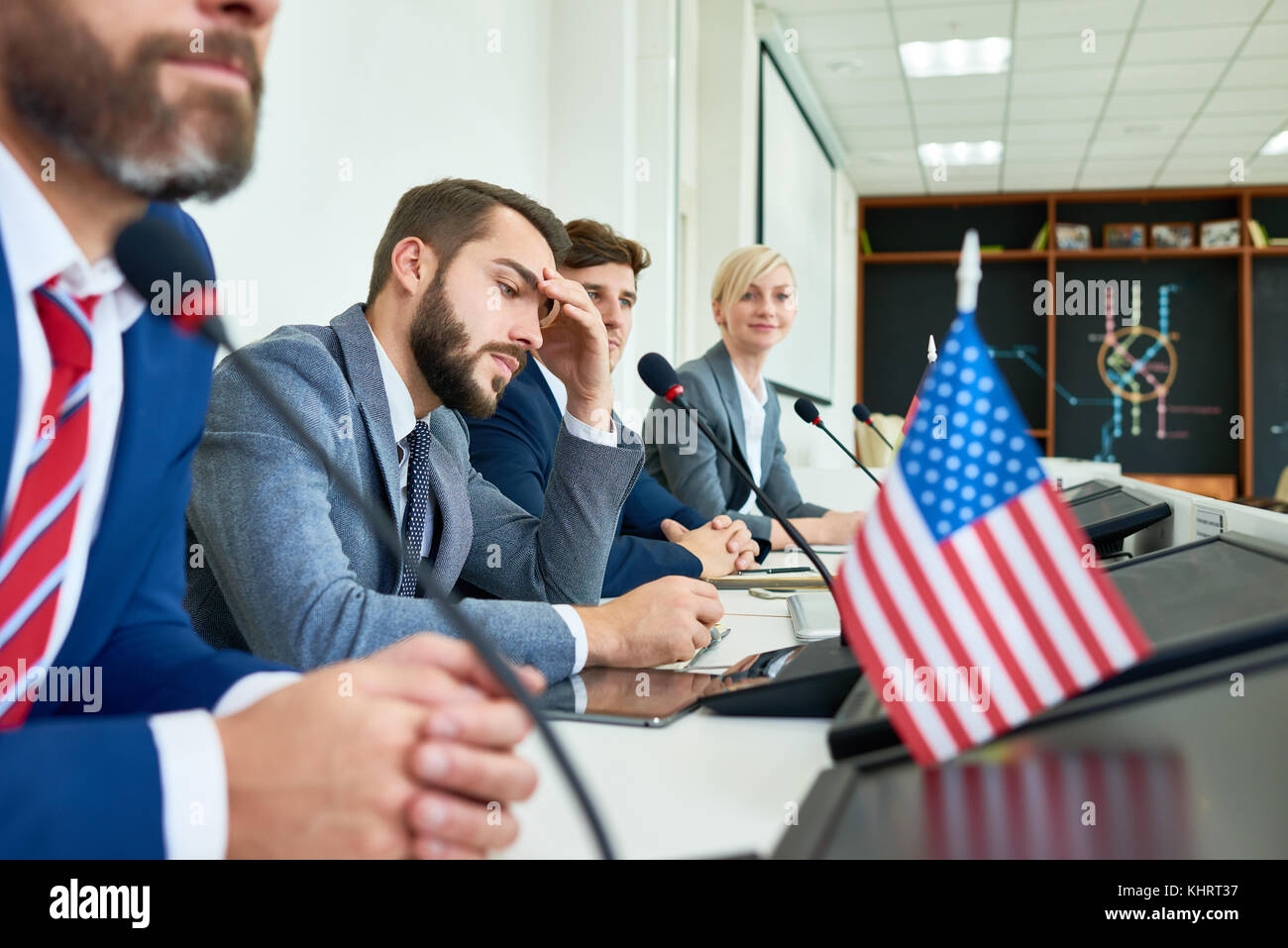 Side view of several business people sitting in row participating in ...