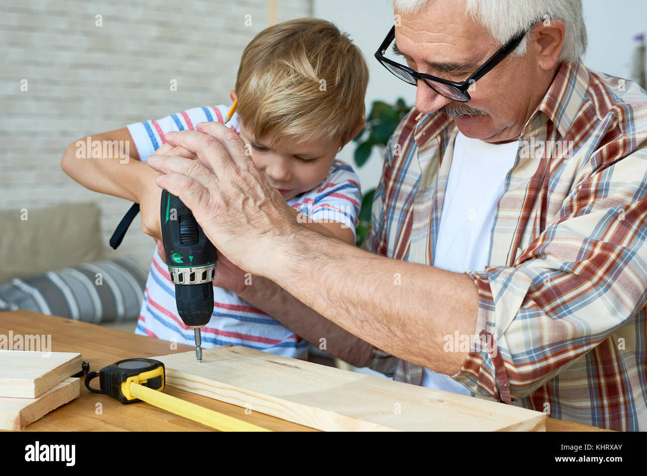 Portrait of senior man helping little boy make wooden model, teaching ...