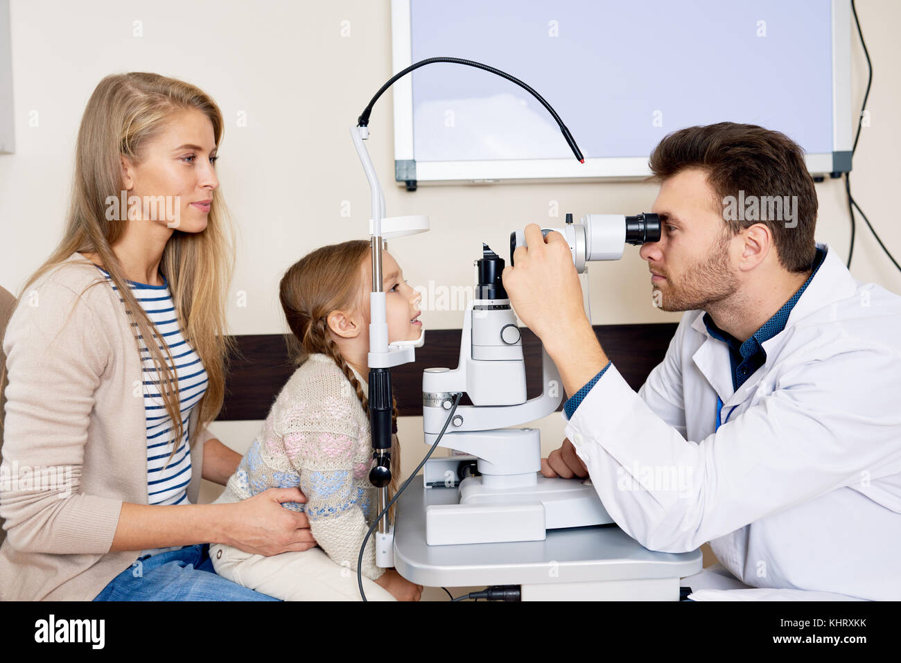 Side view portrait of young optometrist testing sight of little girl ...