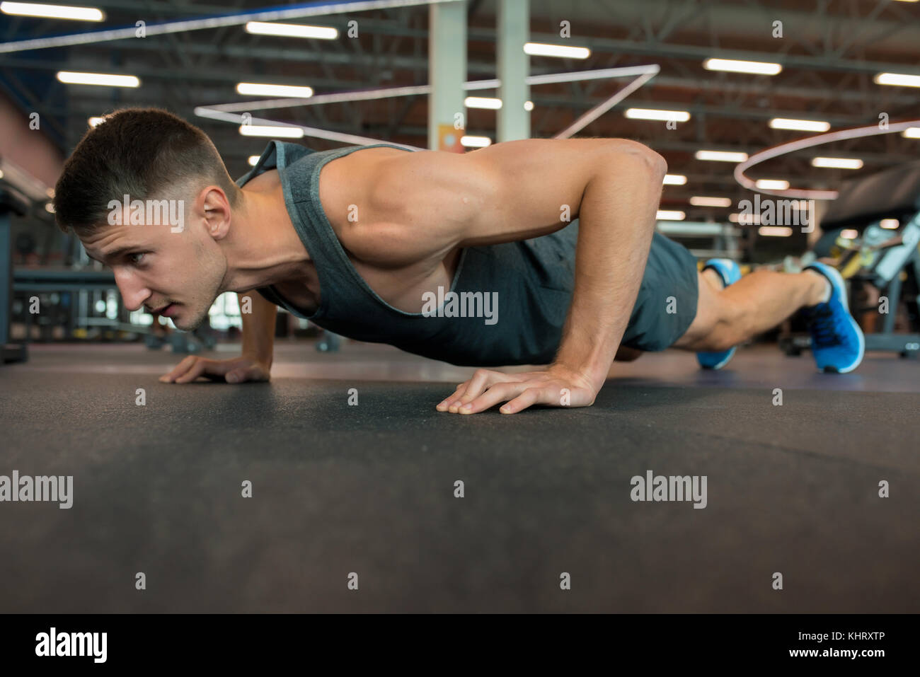 Full length portrait of handsome young man doing push-up exercise while working out on floor in ...