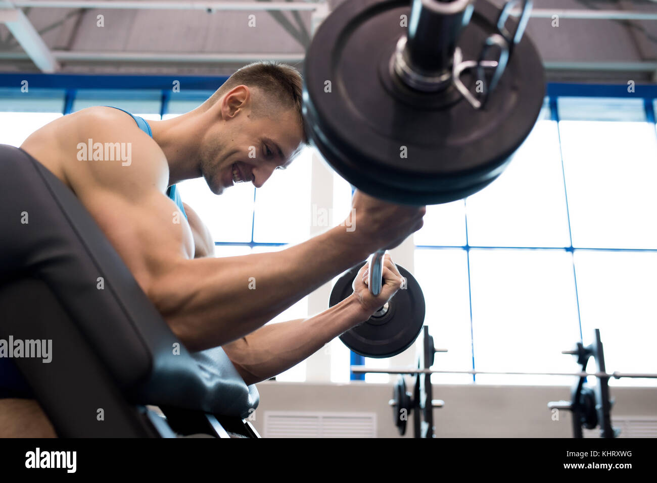 Side view portrait of handsome young man lifting barbell pumping arm ...