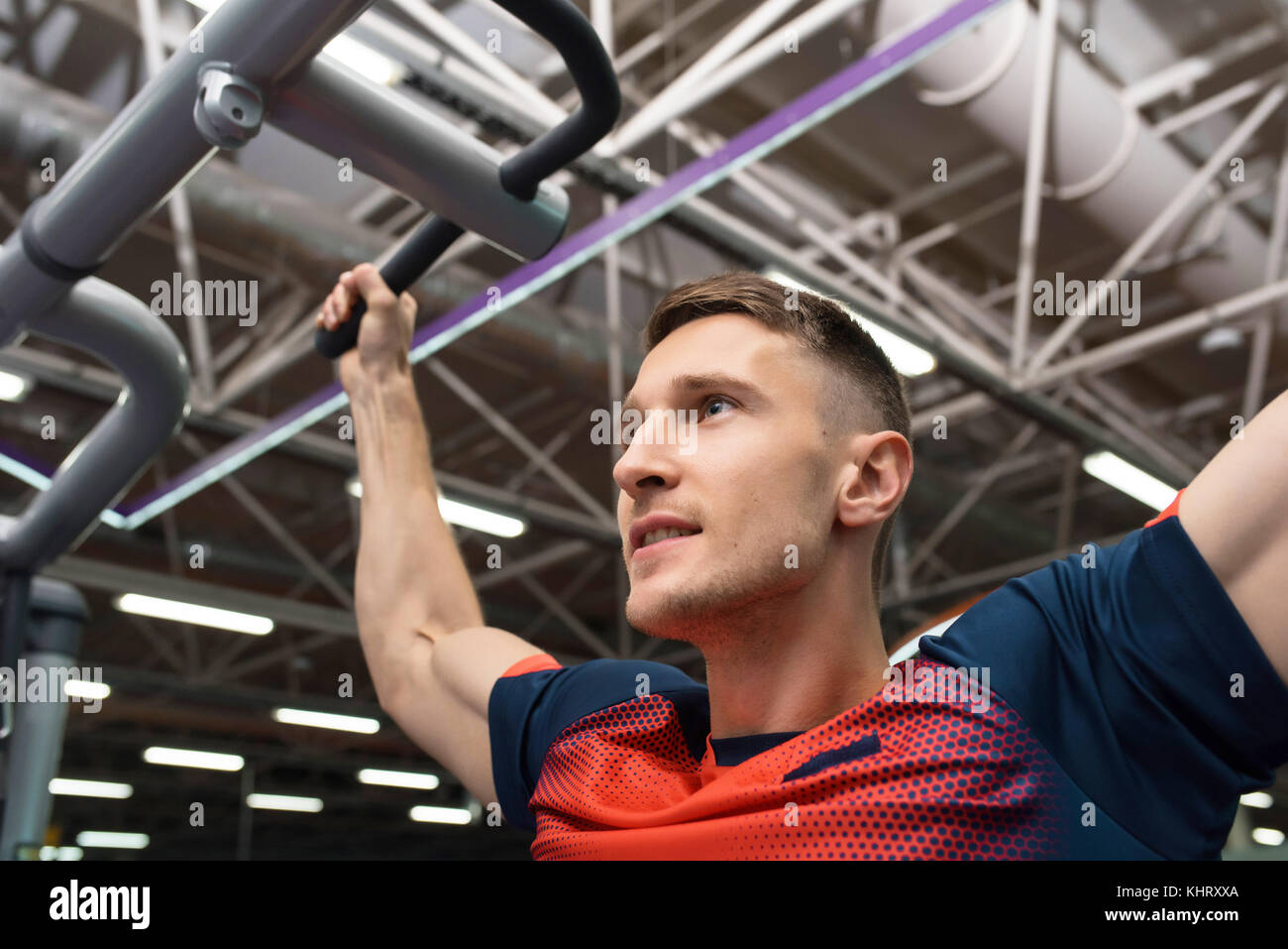 Low angle portrait of strong handsome man using exercise machines ...