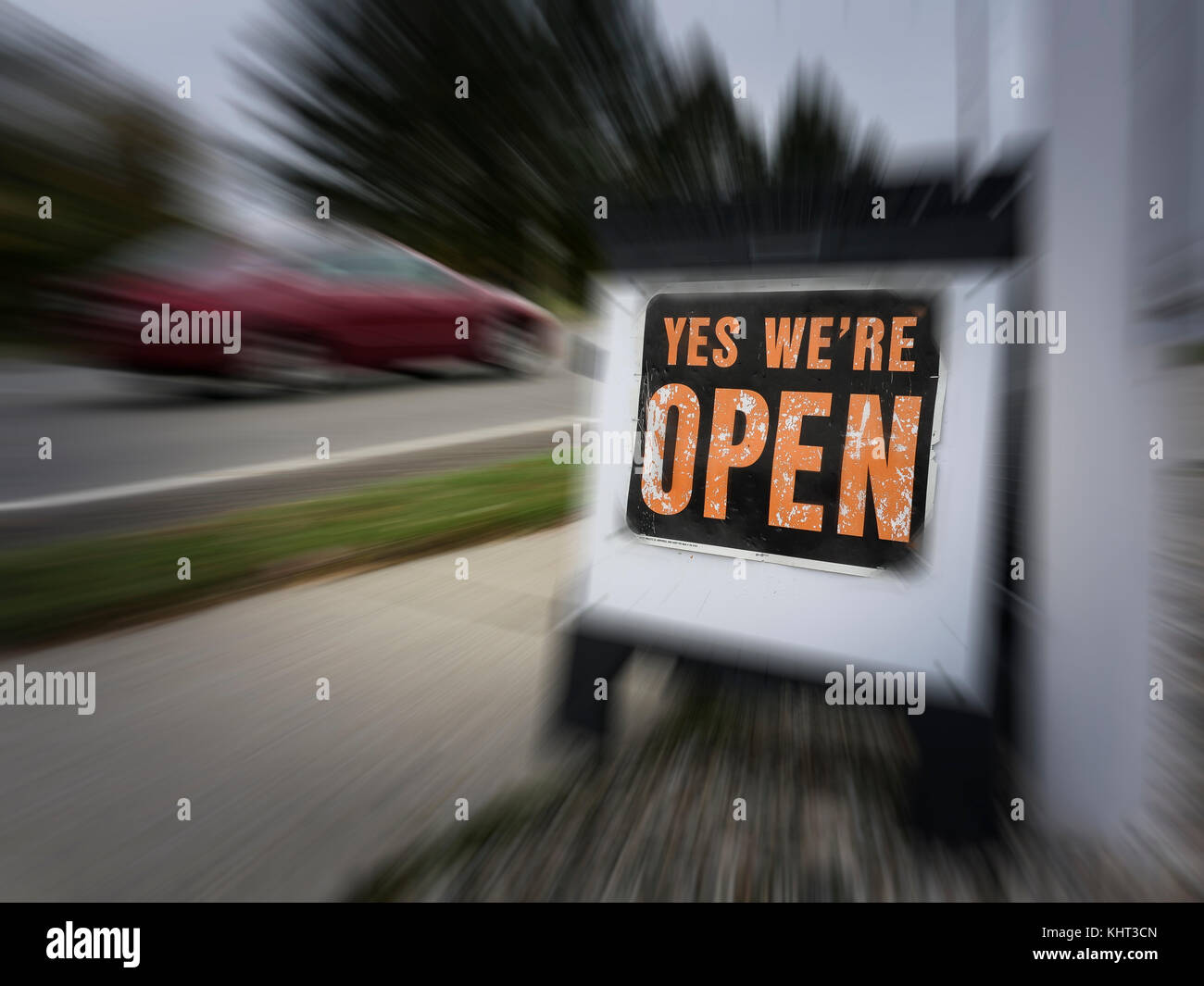 Zoom in on Yes we're open sign placed on a pavement near the road ...