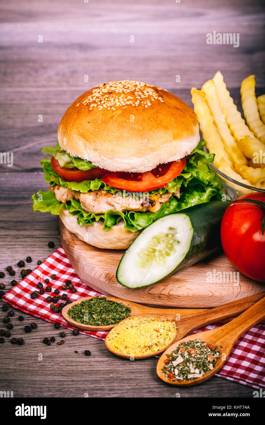 Preparing delicious homemade chicken burger with fries, fresh lettuce ...