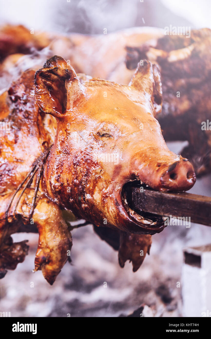 Traditionally suckling pig on a rotating spit with fire and smoke Stock ...