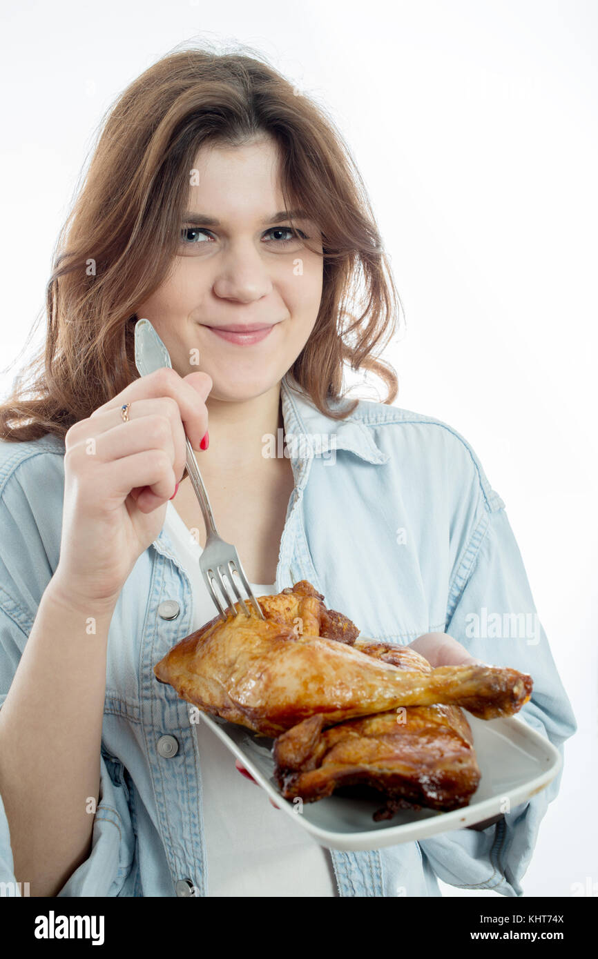 fun young woman eats fried chicken thigh on white background isolated ...