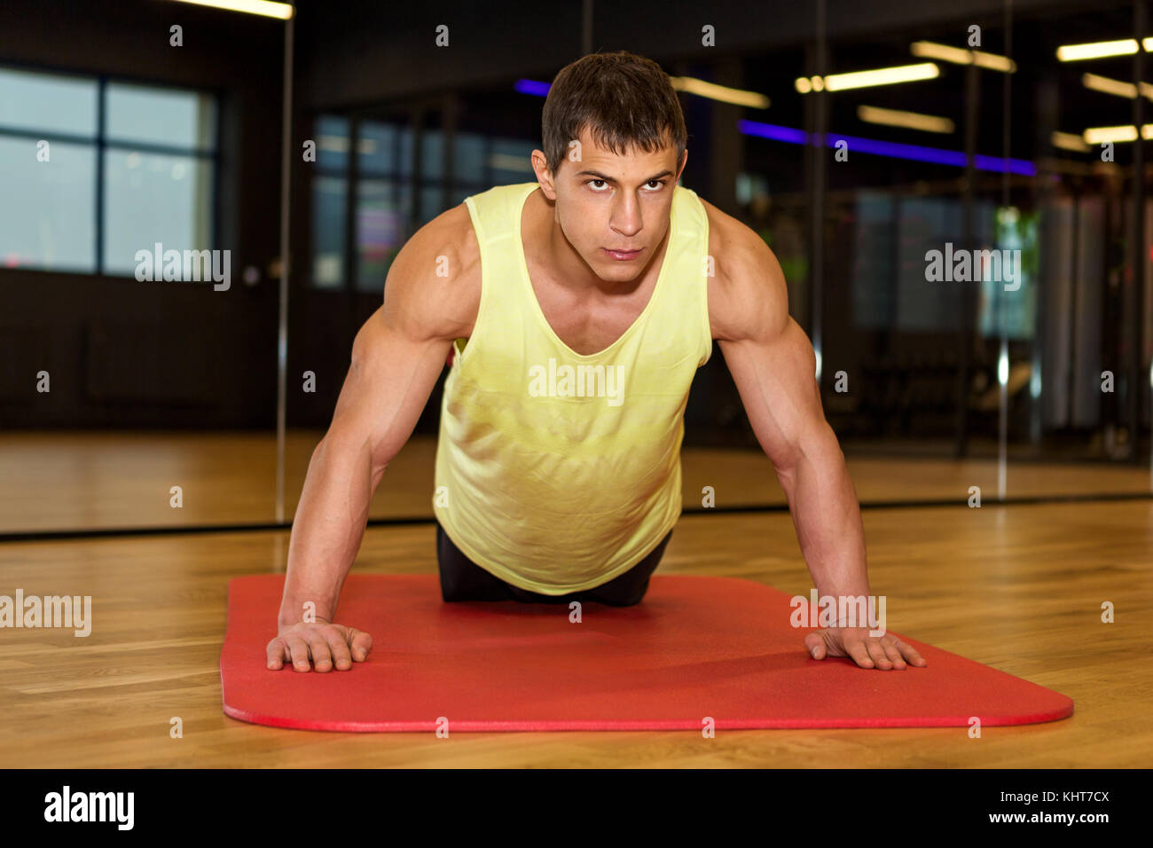 Young muscle man doing push ups in gym. Bodybuilder male working out in ...