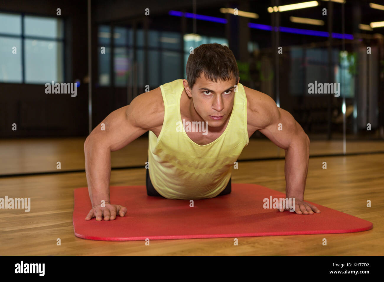Young muscle man doing push ups in gym. Bodybuilder male working out in ...