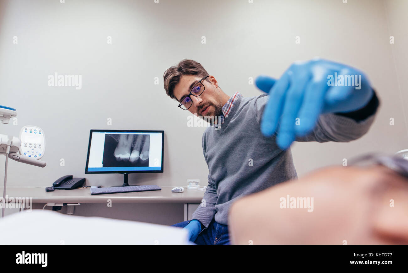 Male dentist instructing female patient to position her mouth for x-ray ...