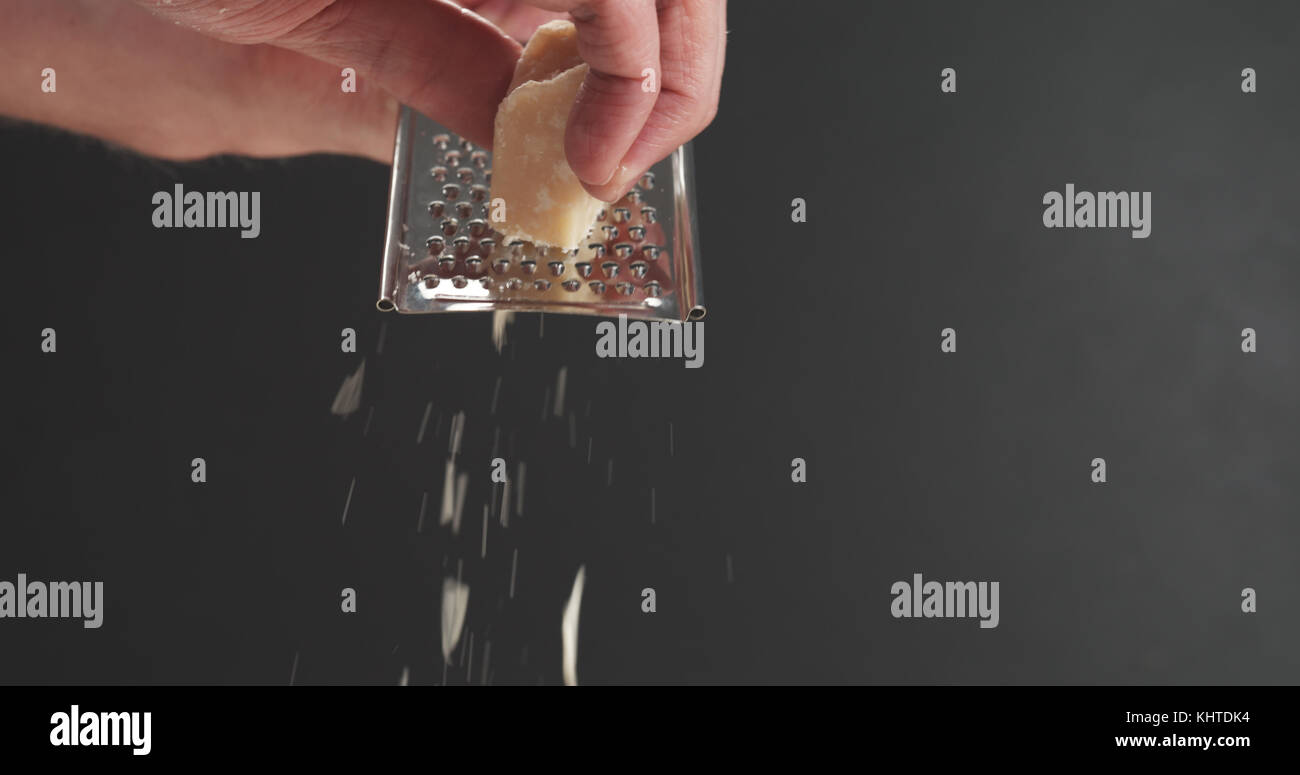 closeup of grating aged parmesan over dark background Stock Photo - Alamy