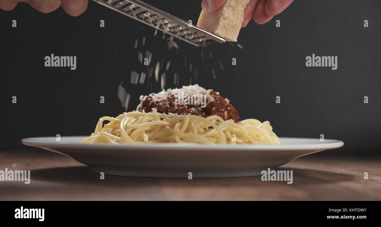 sprinkle grated aged parmesan cheese over spaghetti bolognese Stock ...