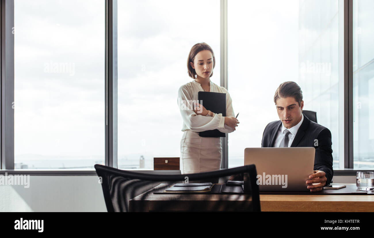 Two business people looking at laptop while working in the office ...