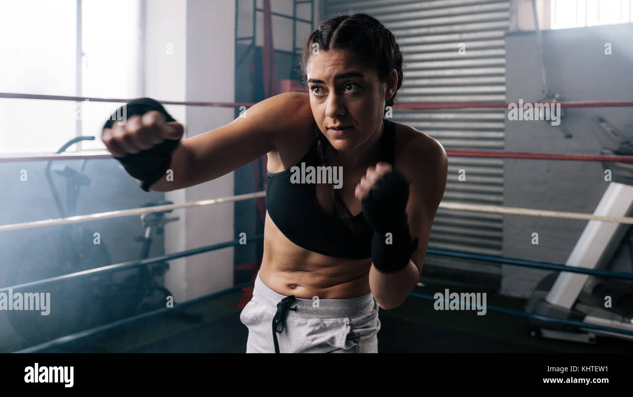 Female boxer doing shadow boxing inside a boxing ring. Boxer practicing ...