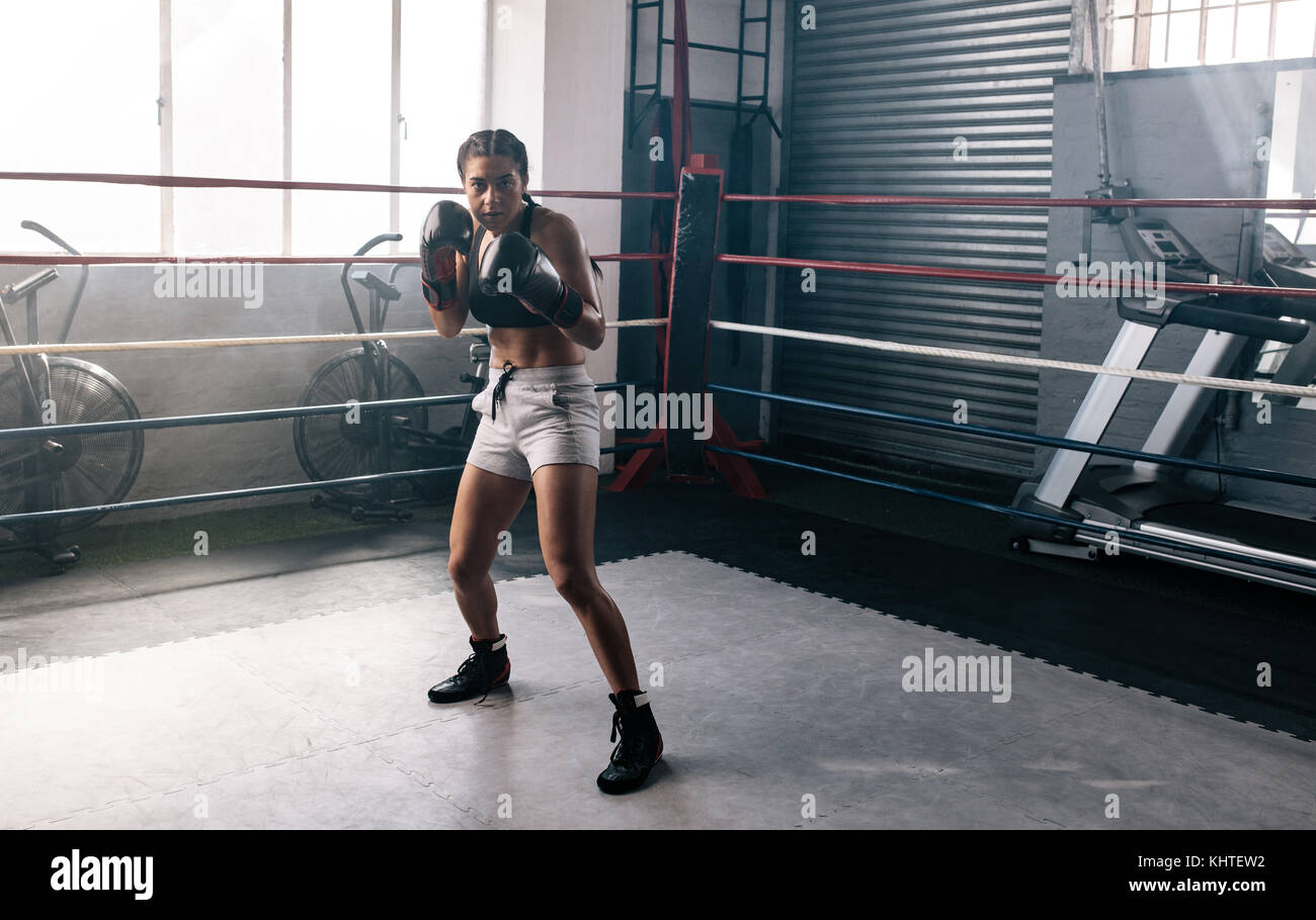 Female boxer doing shadow boxing inside a boxing ring. Boxer practicing ...