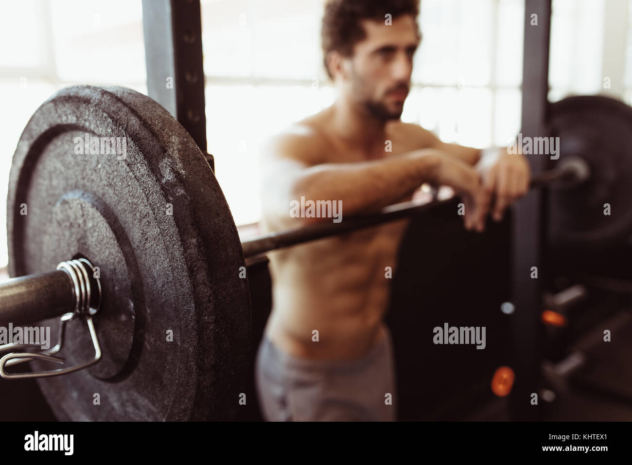 Muscular man leaning over barbell after training in gym. Male taking ...