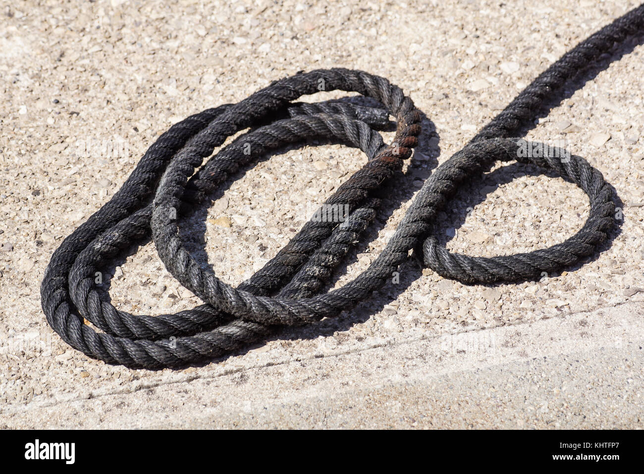 old frayed boat rope on the pier road background Stock Photo - Alamy