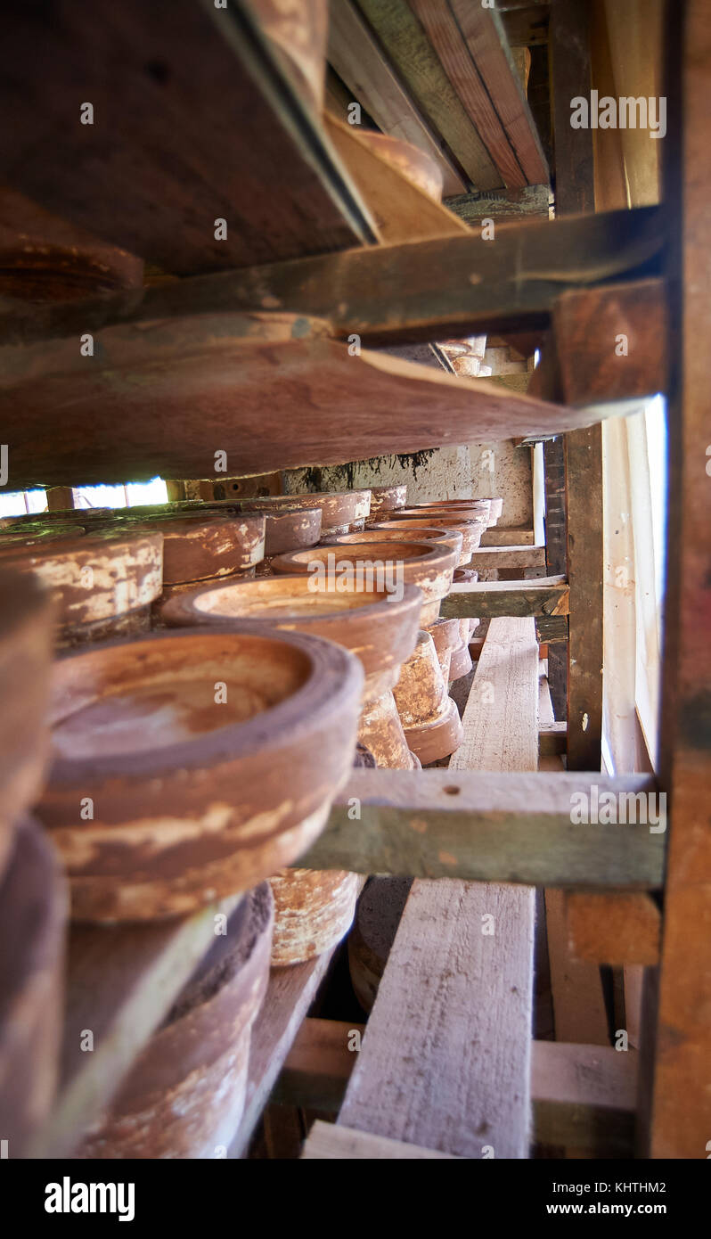 Rows of plaster pottery moulds on wooden shelves in pottery studio ...