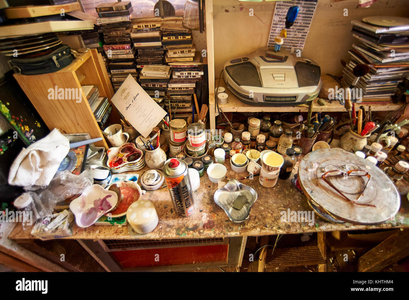 Work bench cluttered with paints and potters wheel in pottery studio ...