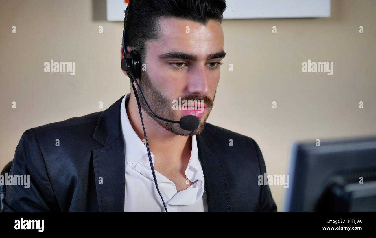 Good looking young man with headset working as help-desk assistant ...