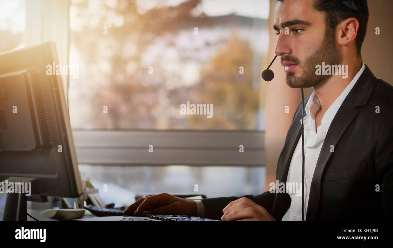 Good looking young man with headset working as help-desk assistant ...