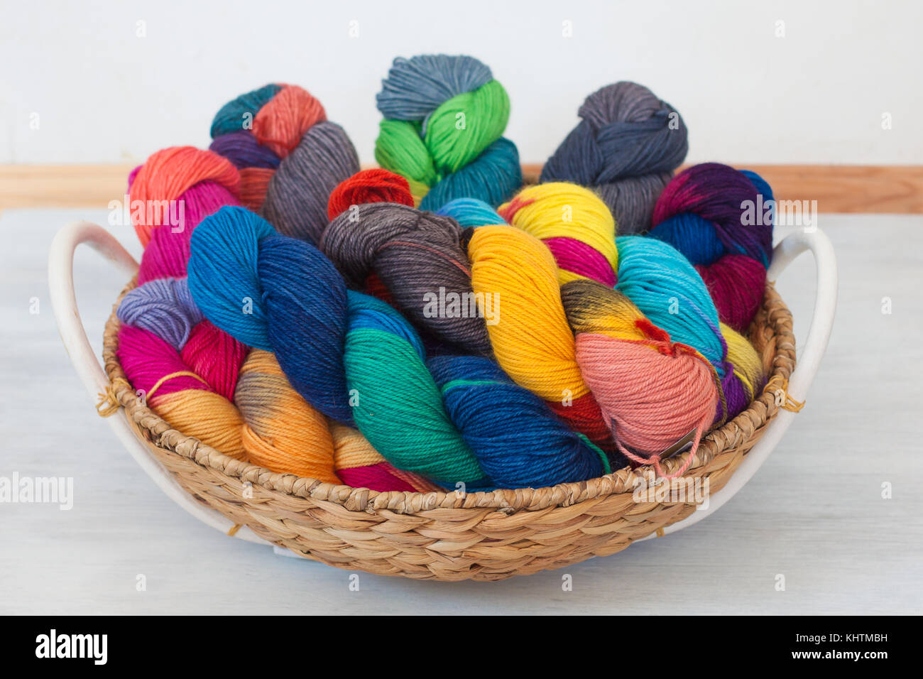 Colourful yarn balls in the basket on the wooden background. Toned ...