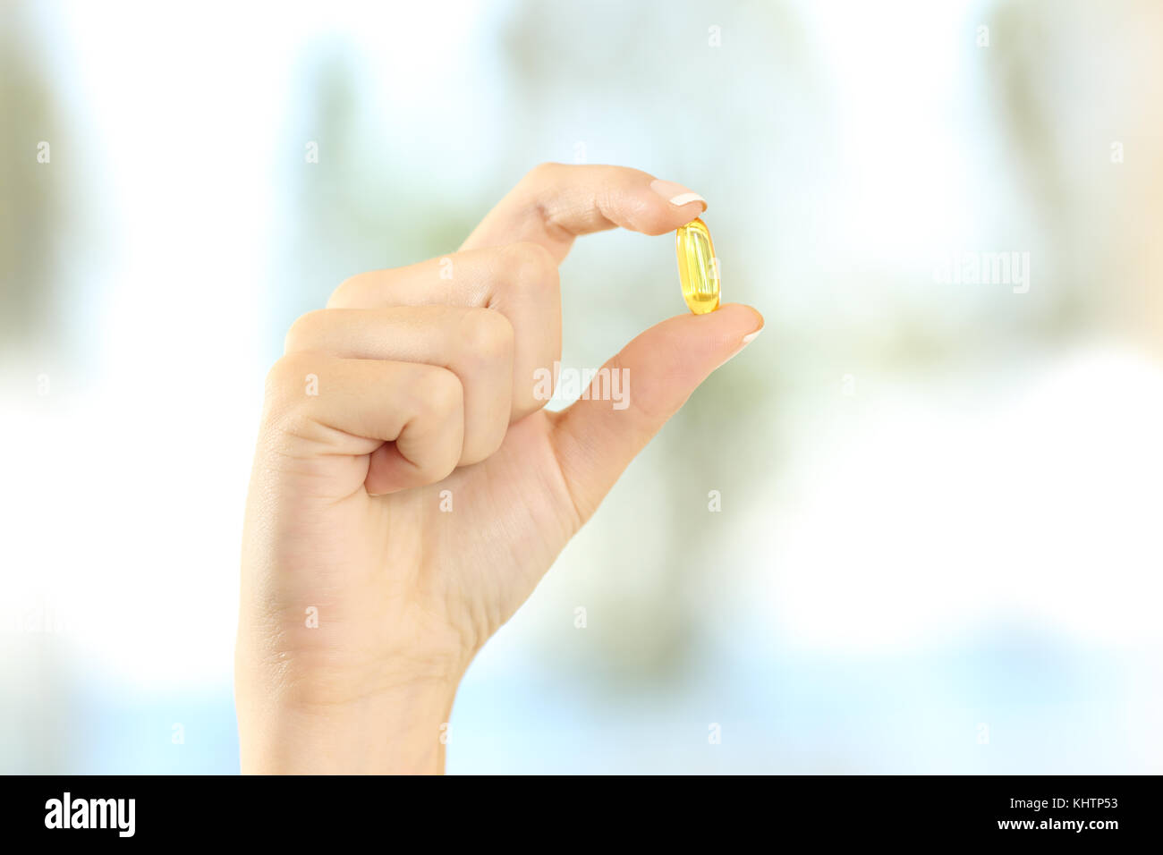 Close up of a woman hand holding a yellow vitamin pill Stock Photo - Alamy