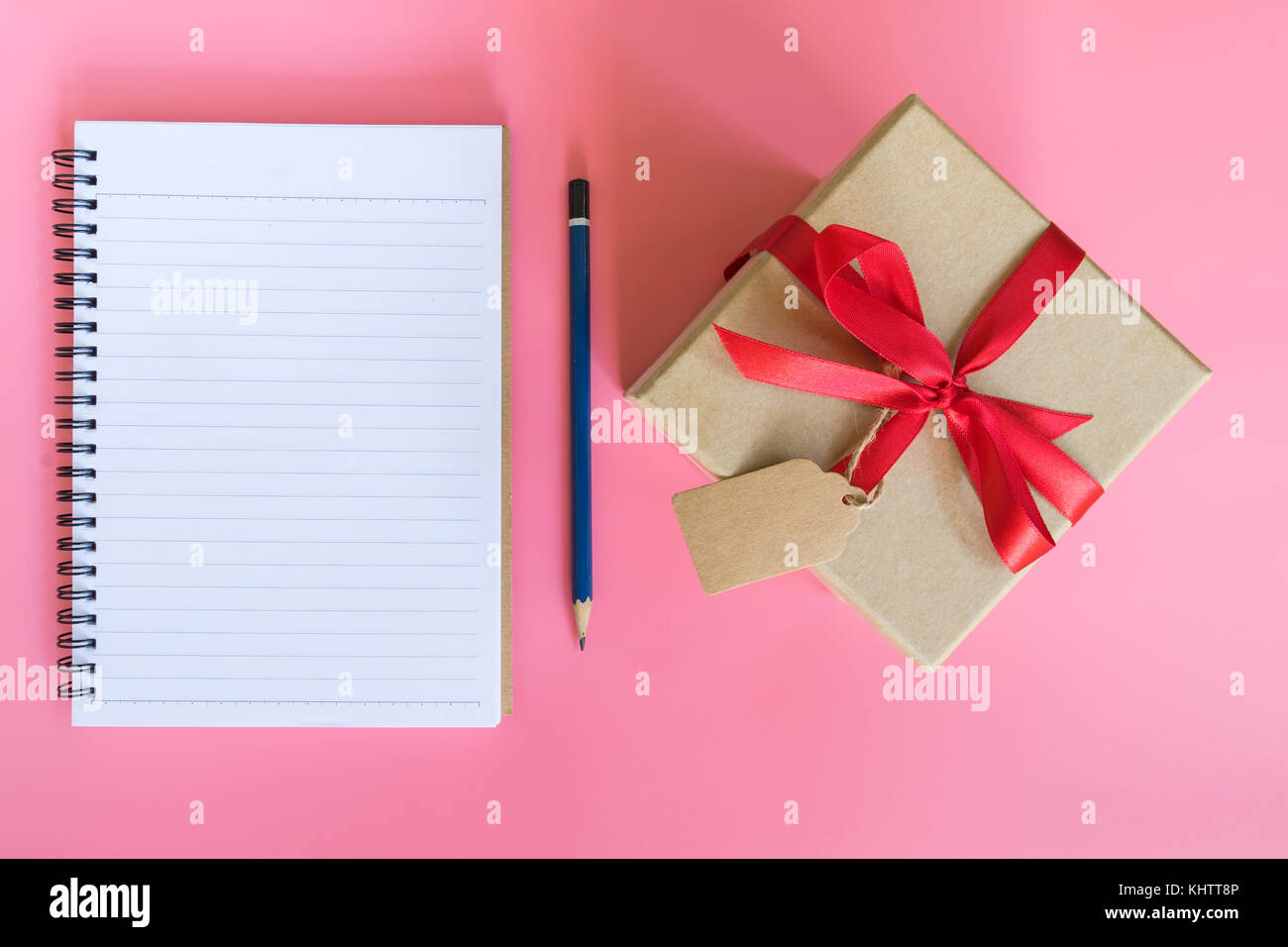 top view brown gift box and notebook paper on pink pastel color ...