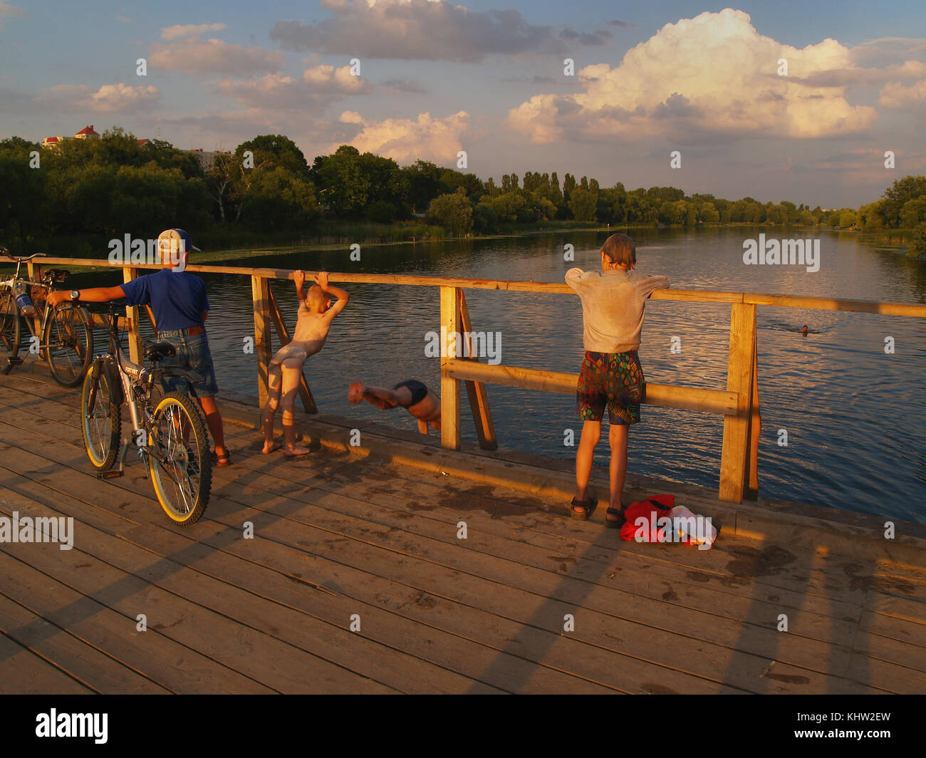 Boys dive from the bridge into the river, summer vacations, children ...