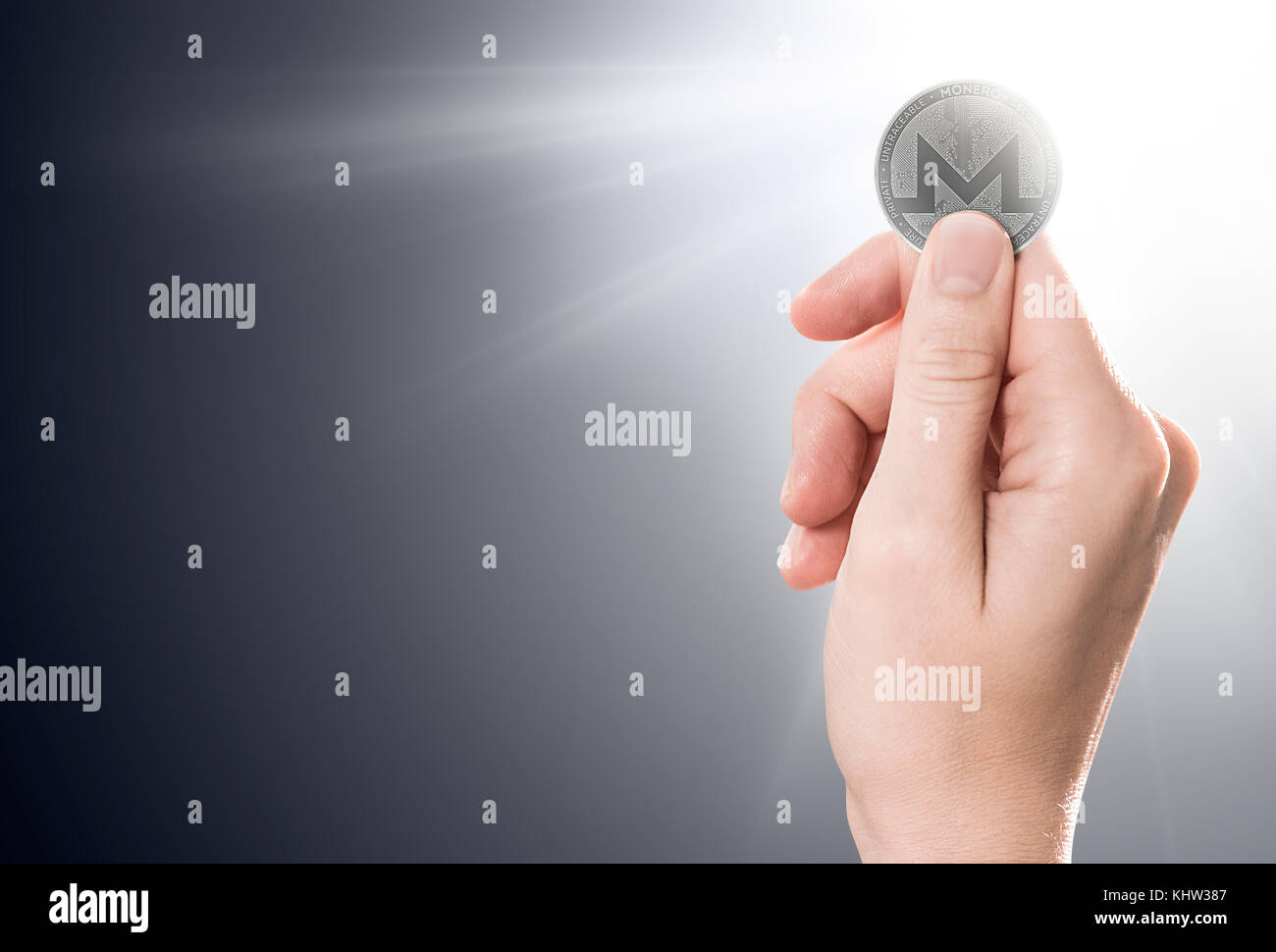 Hand holding a Monero coin on a gently lit background with copy space ...