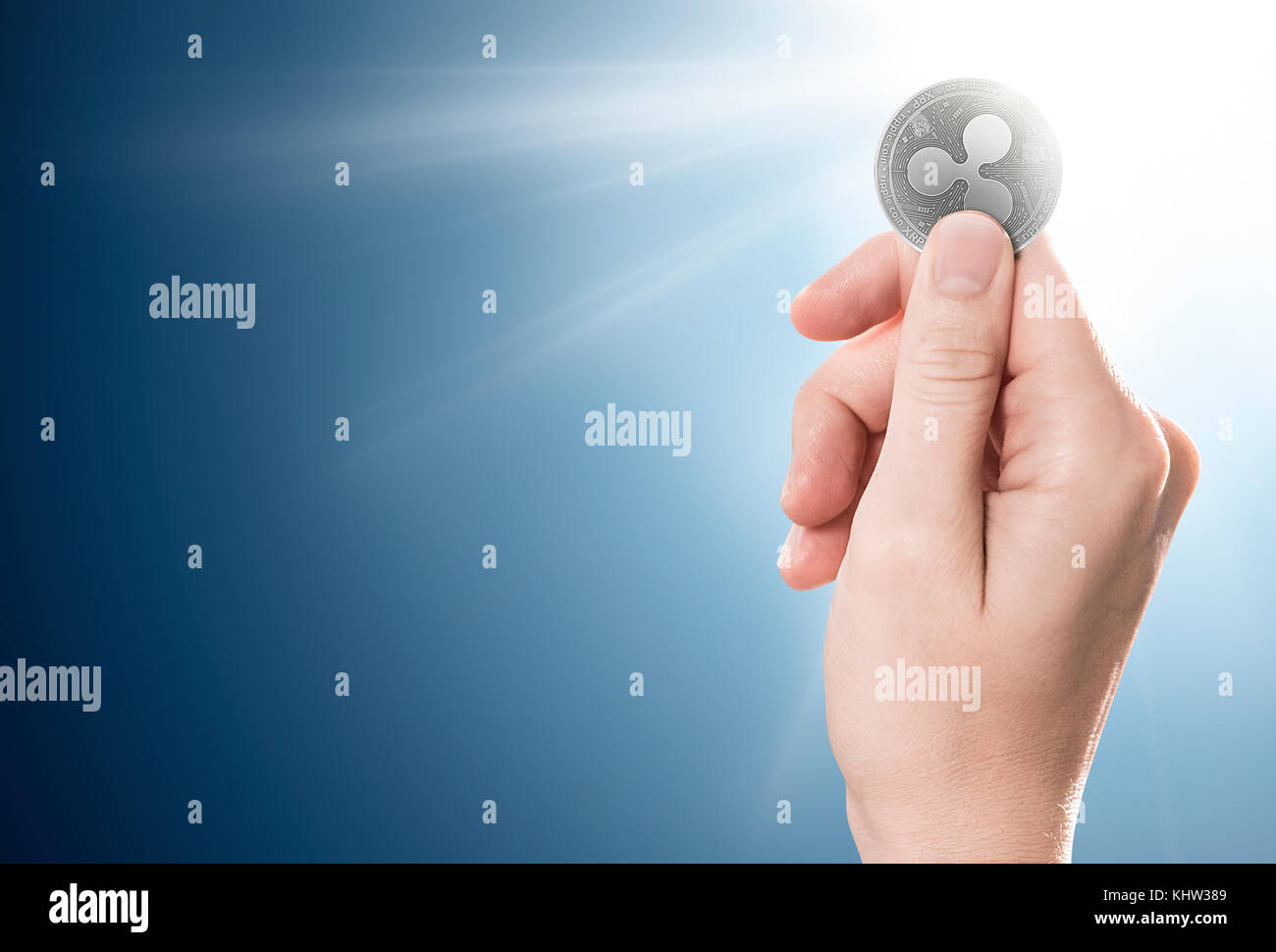 Hand holding a silver Ripple coin on a gently lit background with copy ...
