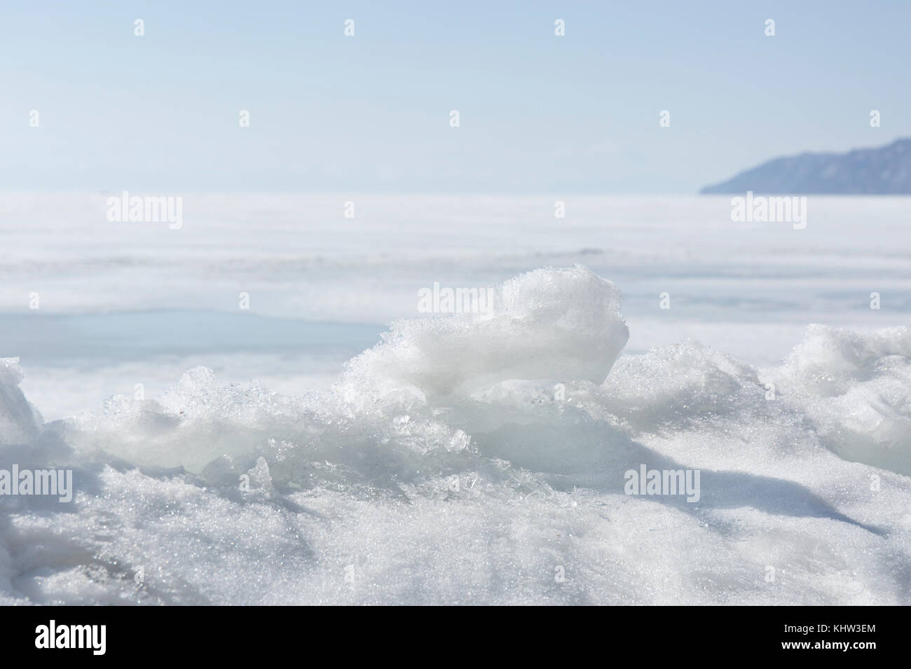 Transparent blue ice hummocks on lake Baikal shore. Siberia winter landscape view. Snow-covered ...