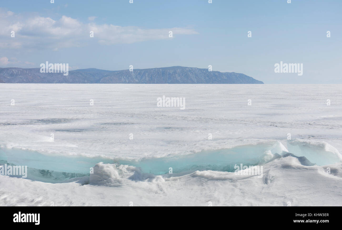 Transparent blue ice hummocks on lake Baikal shore. Siberia winter landscape view. Snow-covered ...