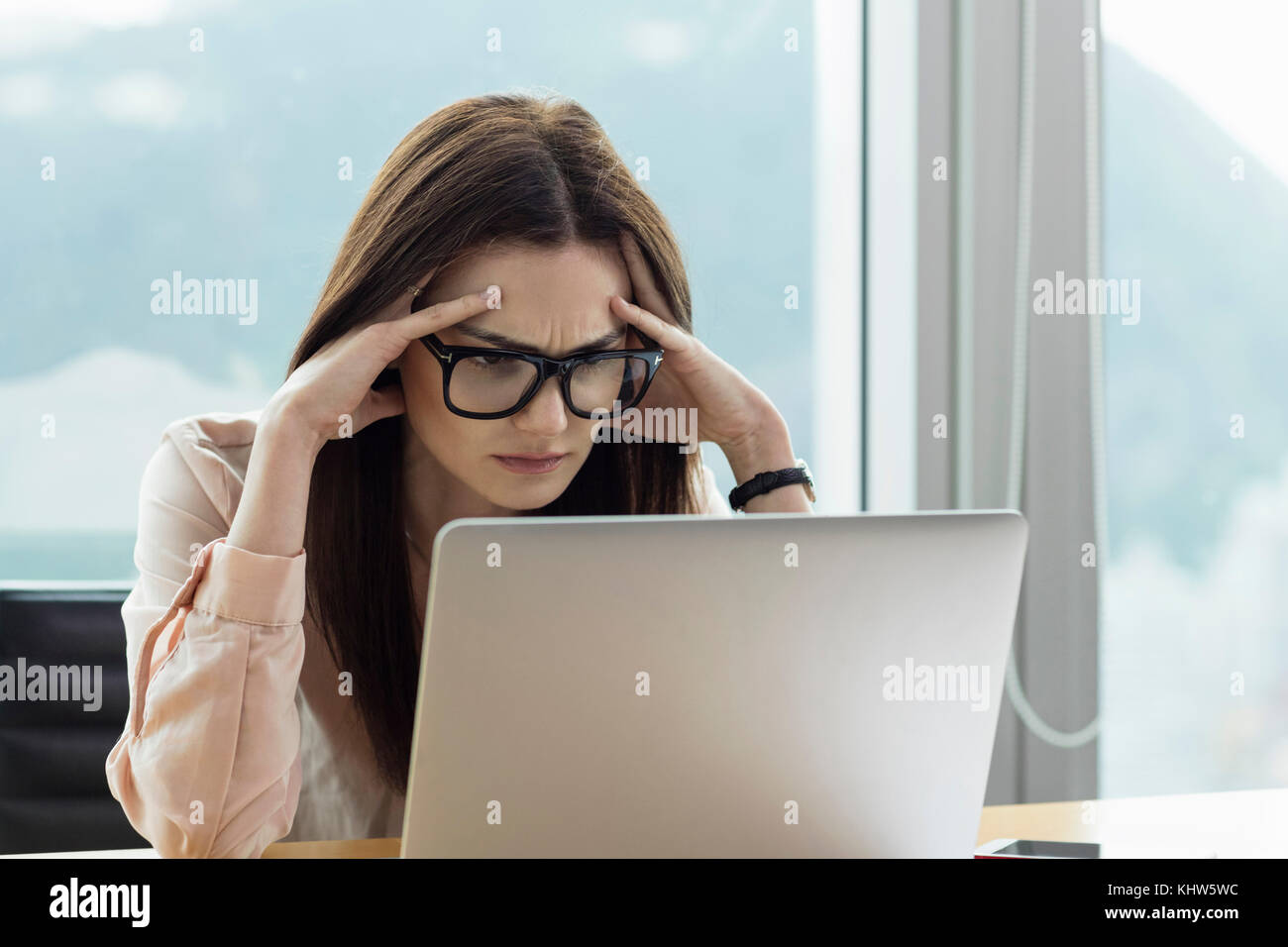 Woman using laptop, head in hands looking stressed Stock Photo - Alamy