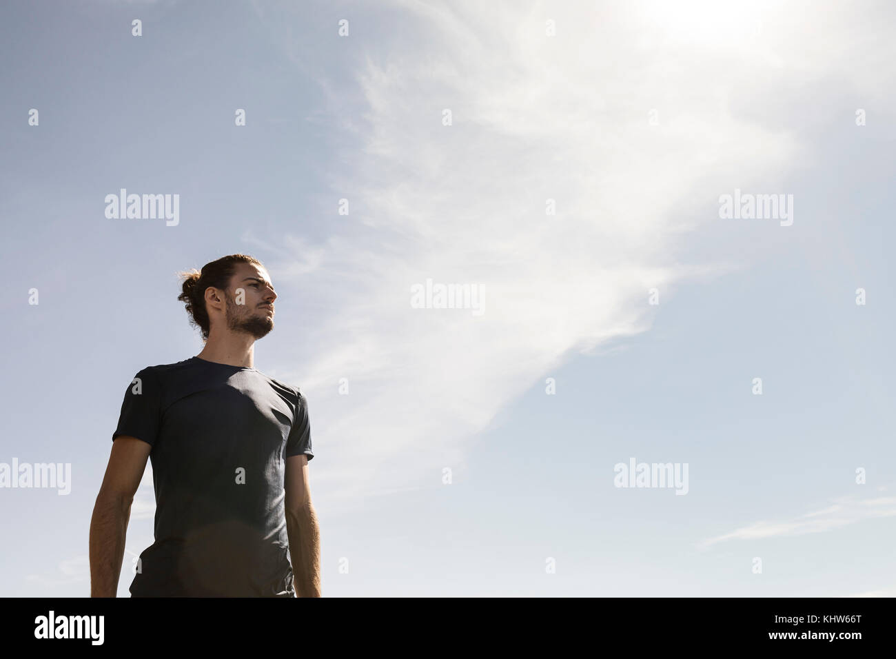 Young male runner gazing against blue sky Stock Photo - Alamy