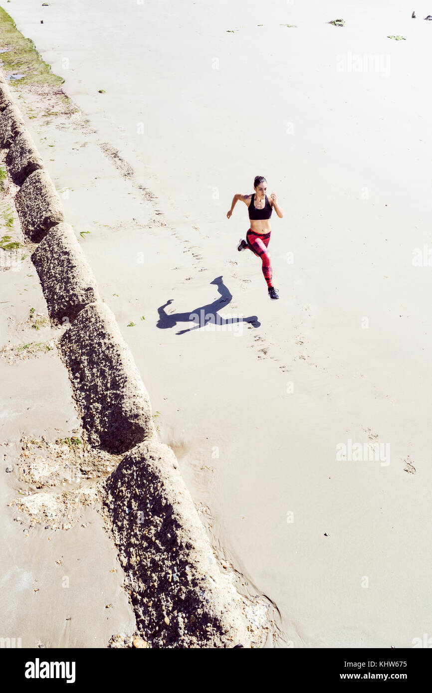 Young woman running along beach, elevated view Stock Photo - Alamy