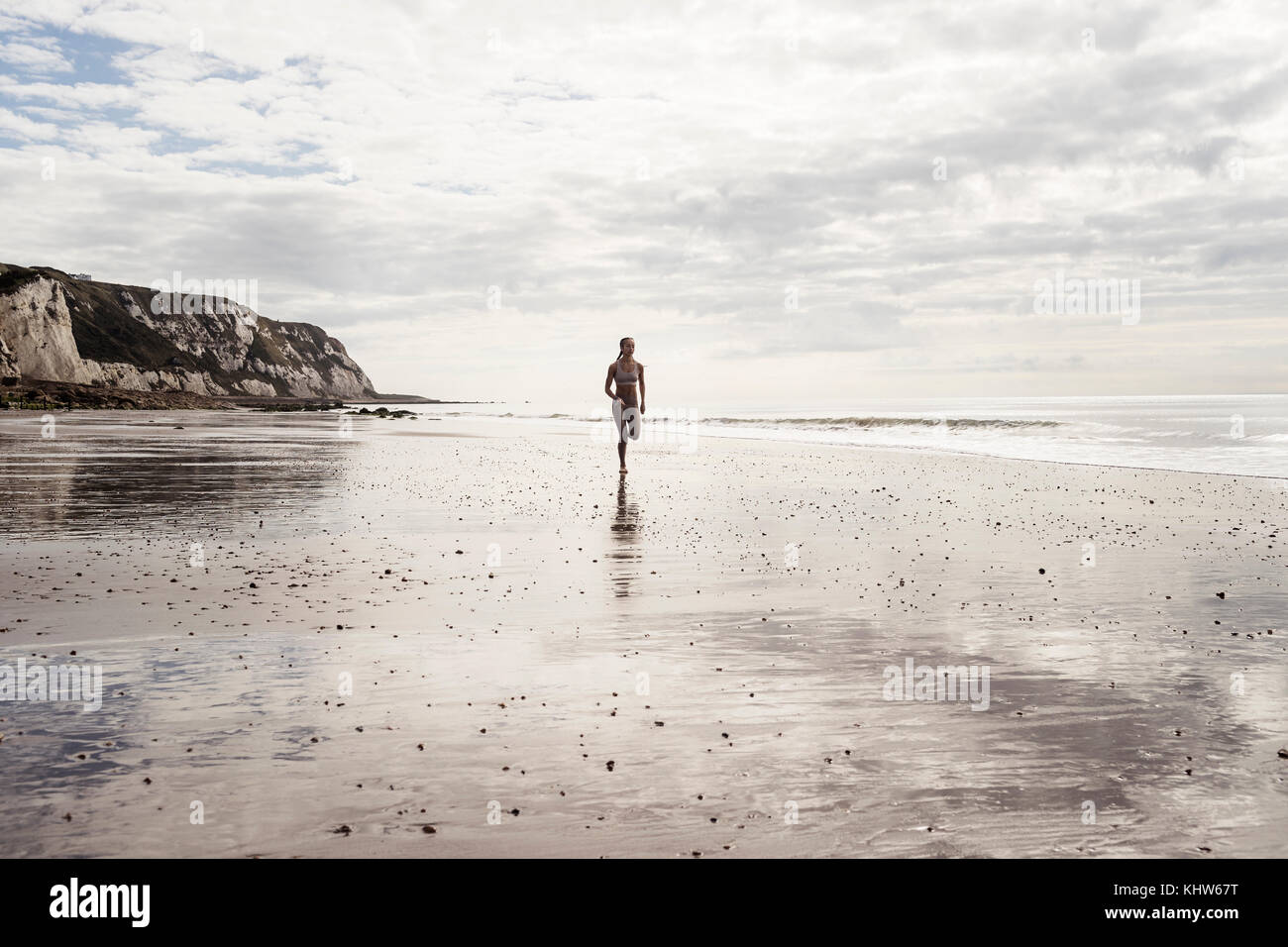 Young woman running along beach Stock Photo - Alamy