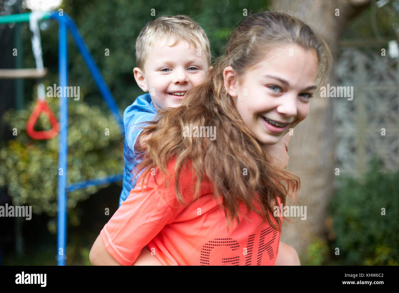 Portrait of young girl carrying young brother on back Stock Photo - Alamy