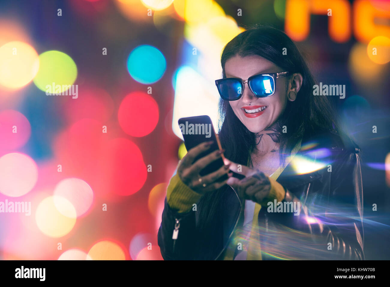 Young woman, outdoors at night, using smartphone, smiling Stock Photo ...