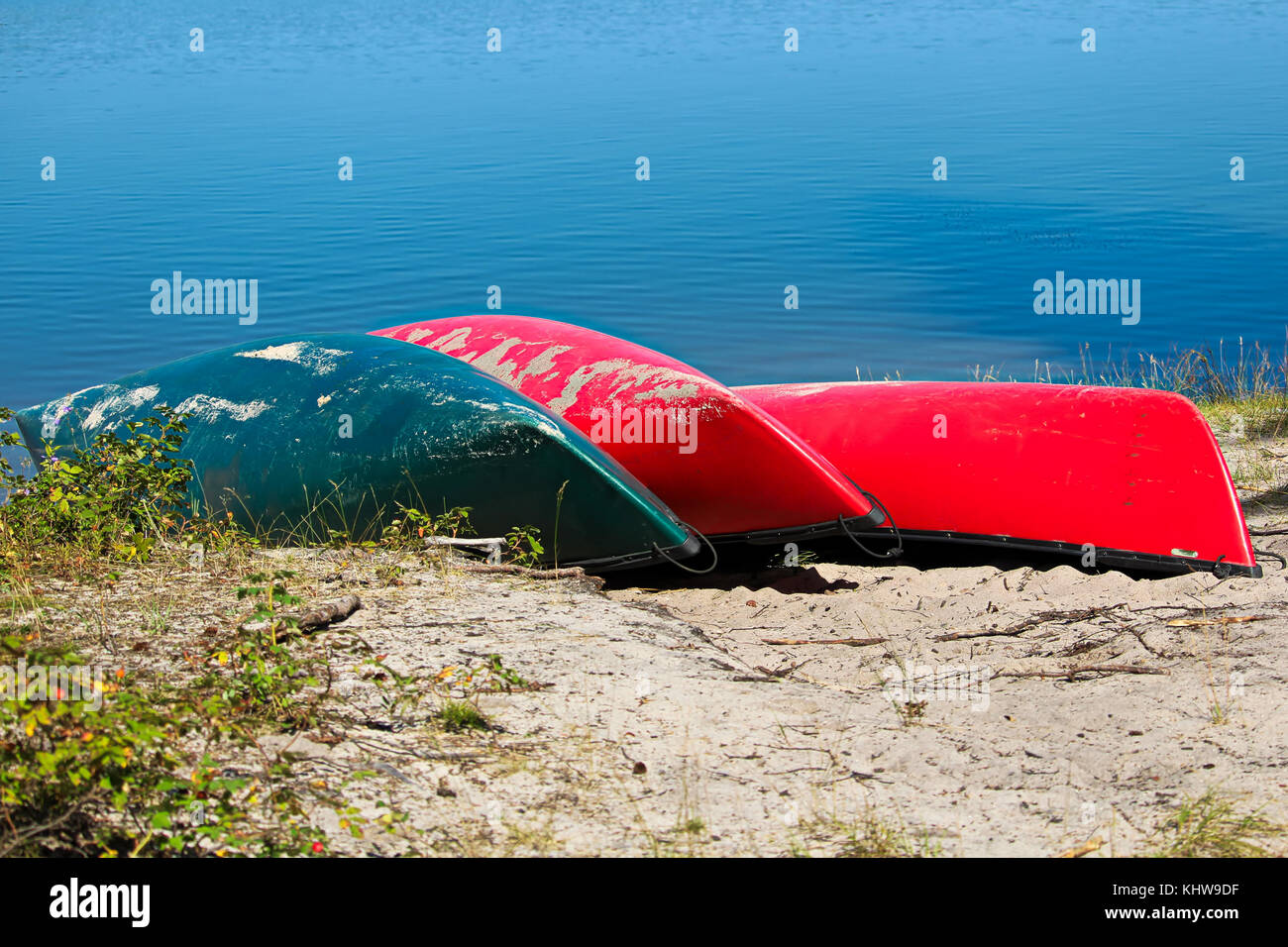 Three overturned canoes along a lake shore Stock Photo - Alamy