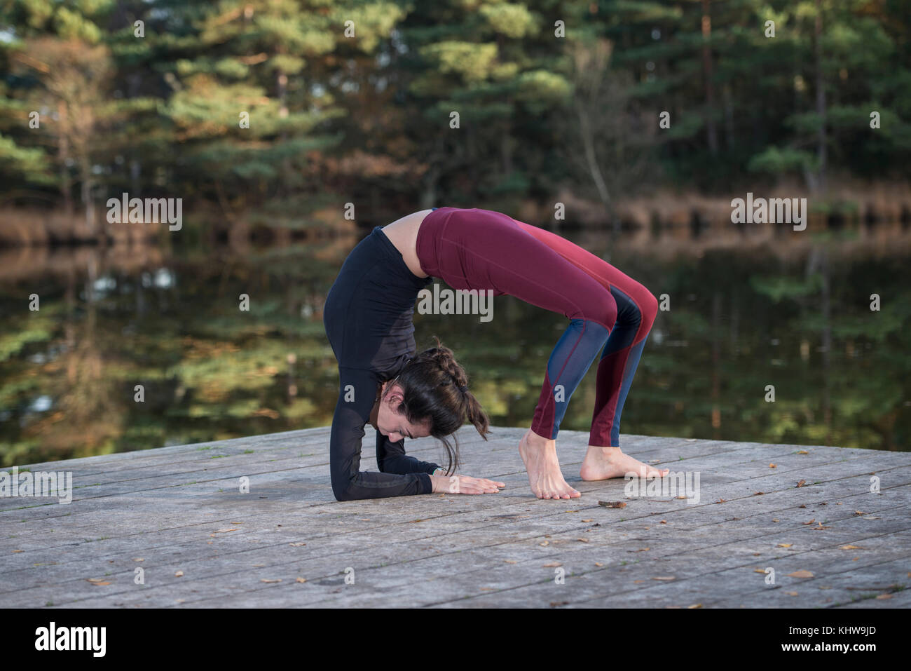 woman practicing yoga by a lake doing a bridge pose Stock Photo - Alamy