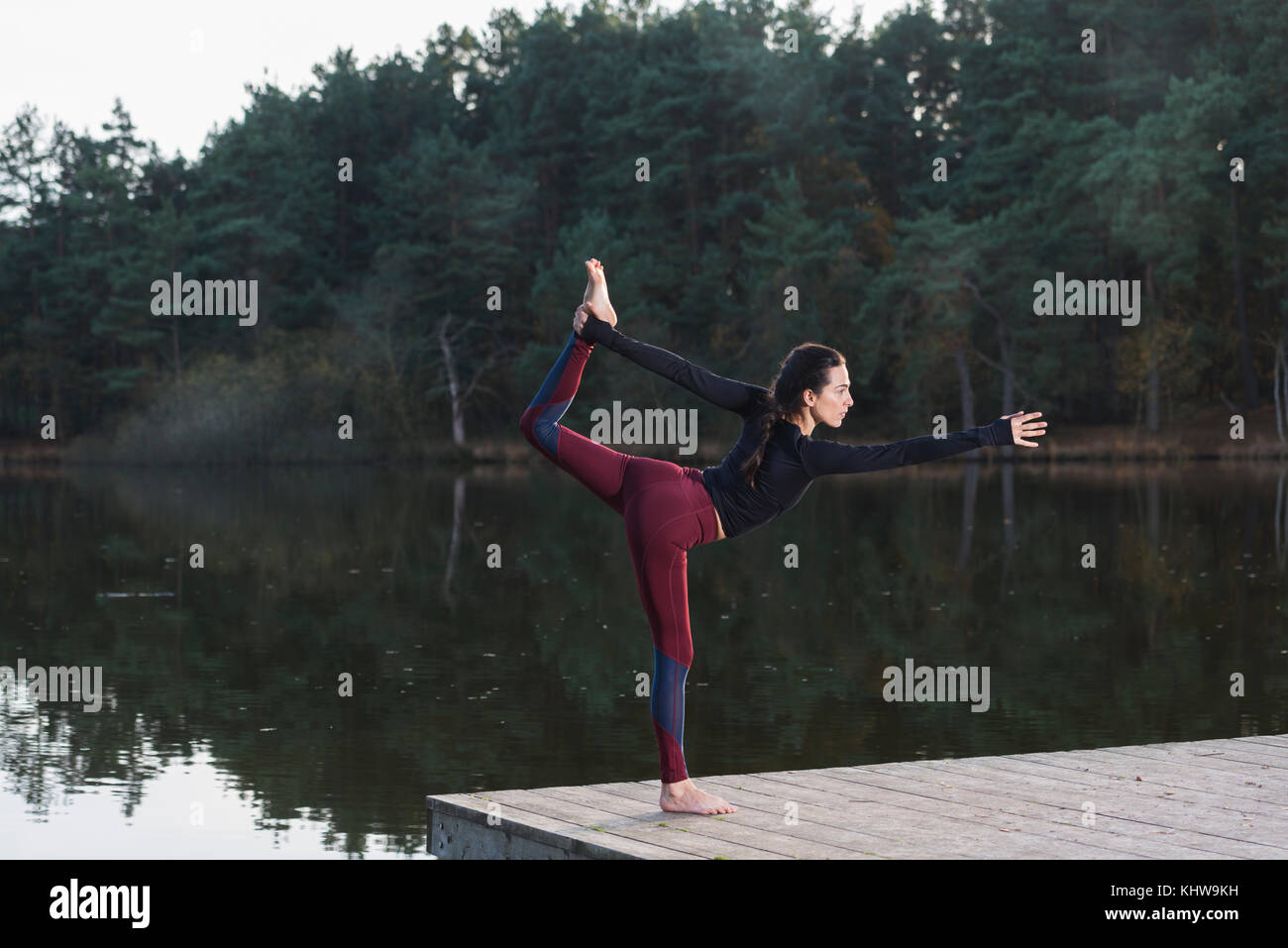 woman practicing yoga by a lake doing the dancers pose Stock Photo - Alamy