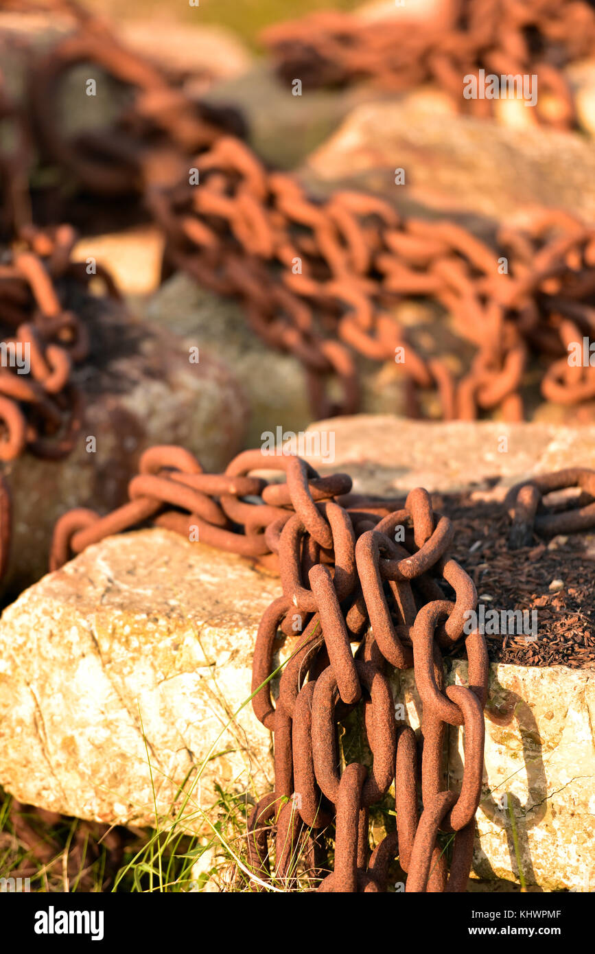 Some rusty and corroded old chains abandoned and left on some rocks on ...