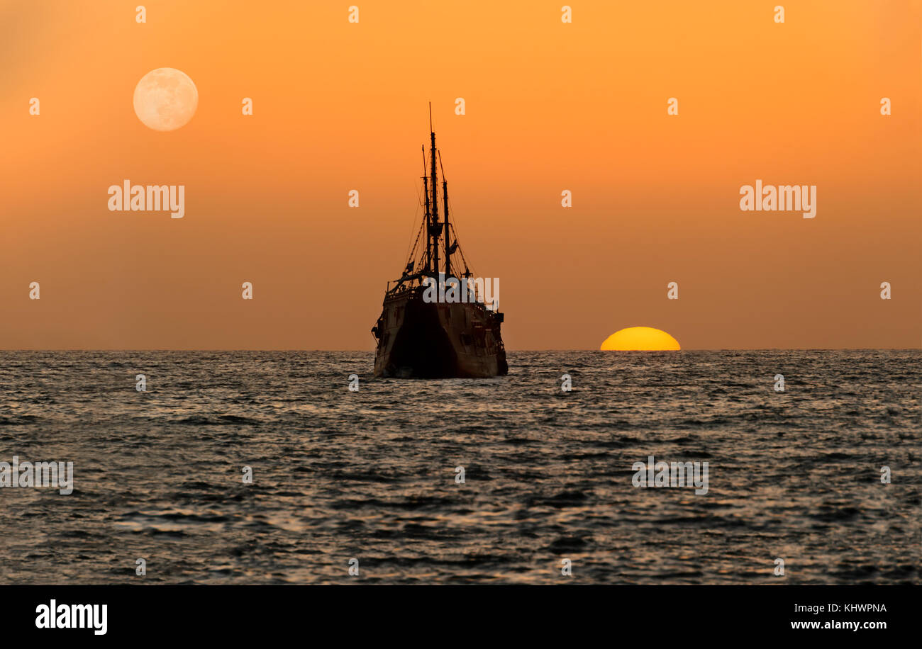 Ocean sunset ship silhouette is an old wooden ship sitting at sea ...