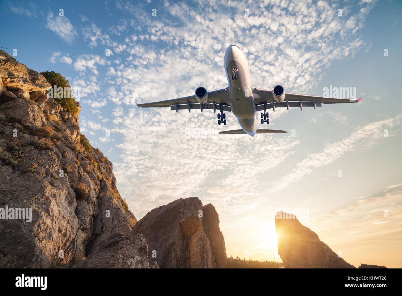 Big white aircraft is flying over rocks at sunset. Landscape with ...