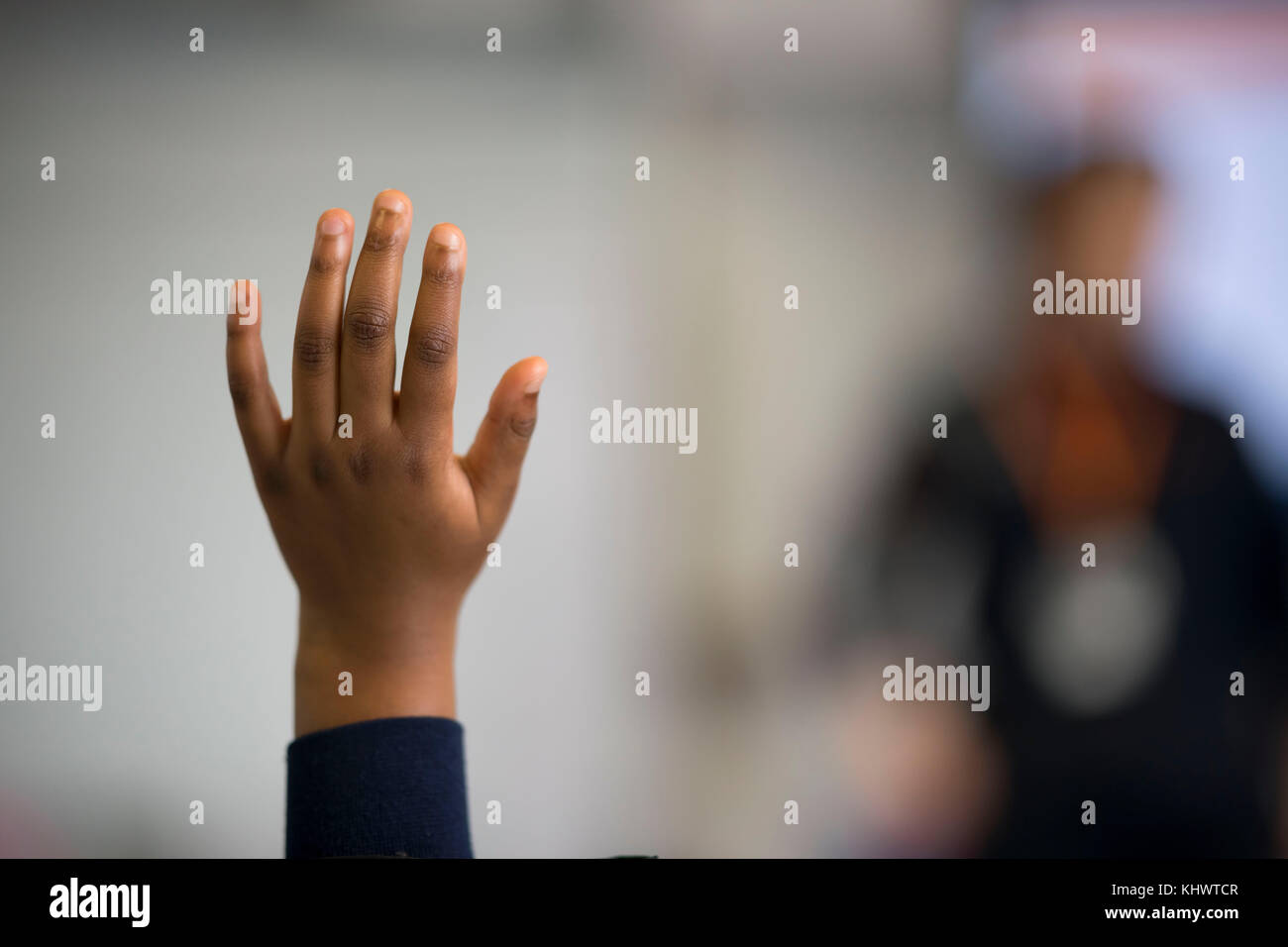 A young black child puts his hand up when asked a question in a school ...