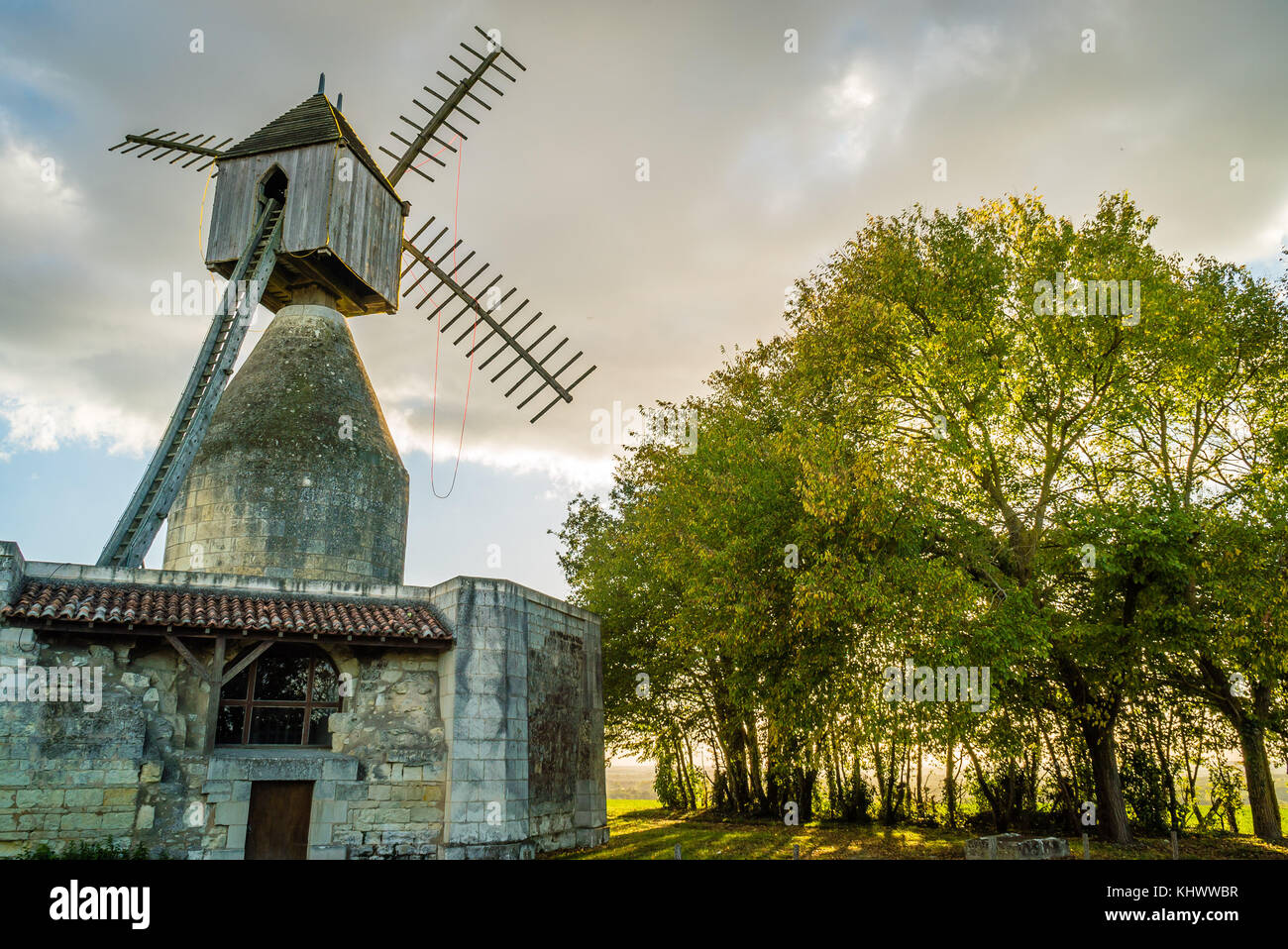 Windmill and trees in France backlit at sunset Stock Photo - Alamy