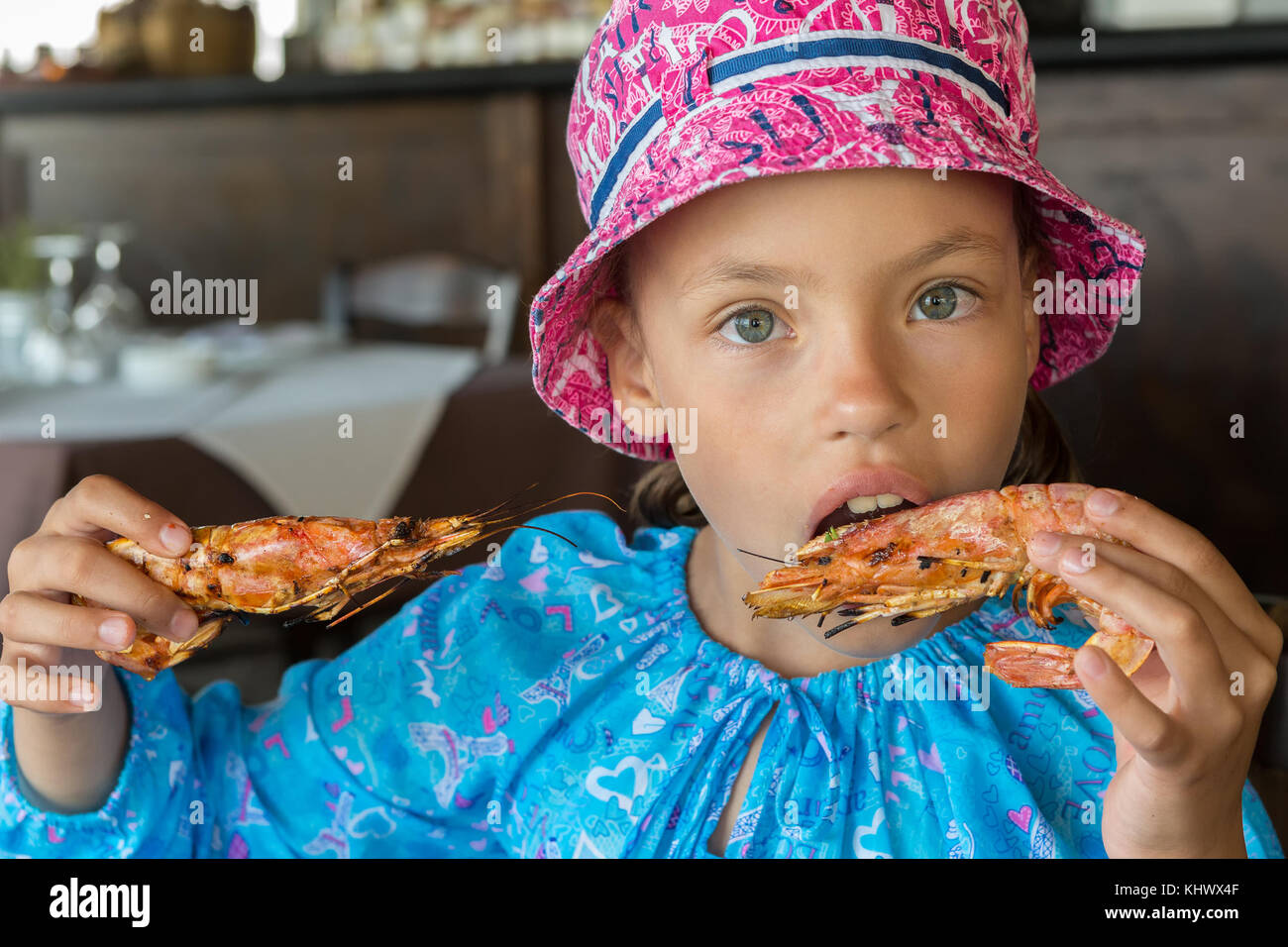 Tourist girl eats large shrimp in cafe on the Sithonia peninsula Stock ...